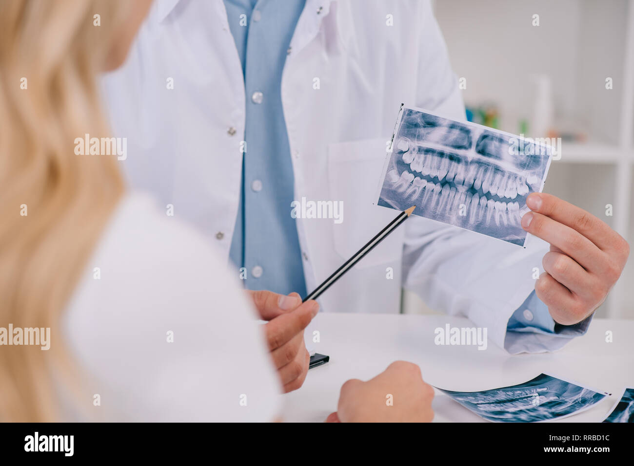 cropped view of orthodontist pointing at teeth x-ray during ...