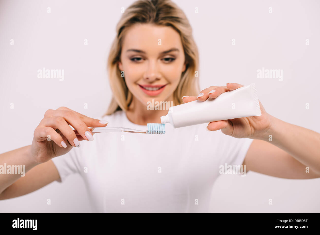 beautiful smiling woman putting toothpaste on toothbrush isolated on ...