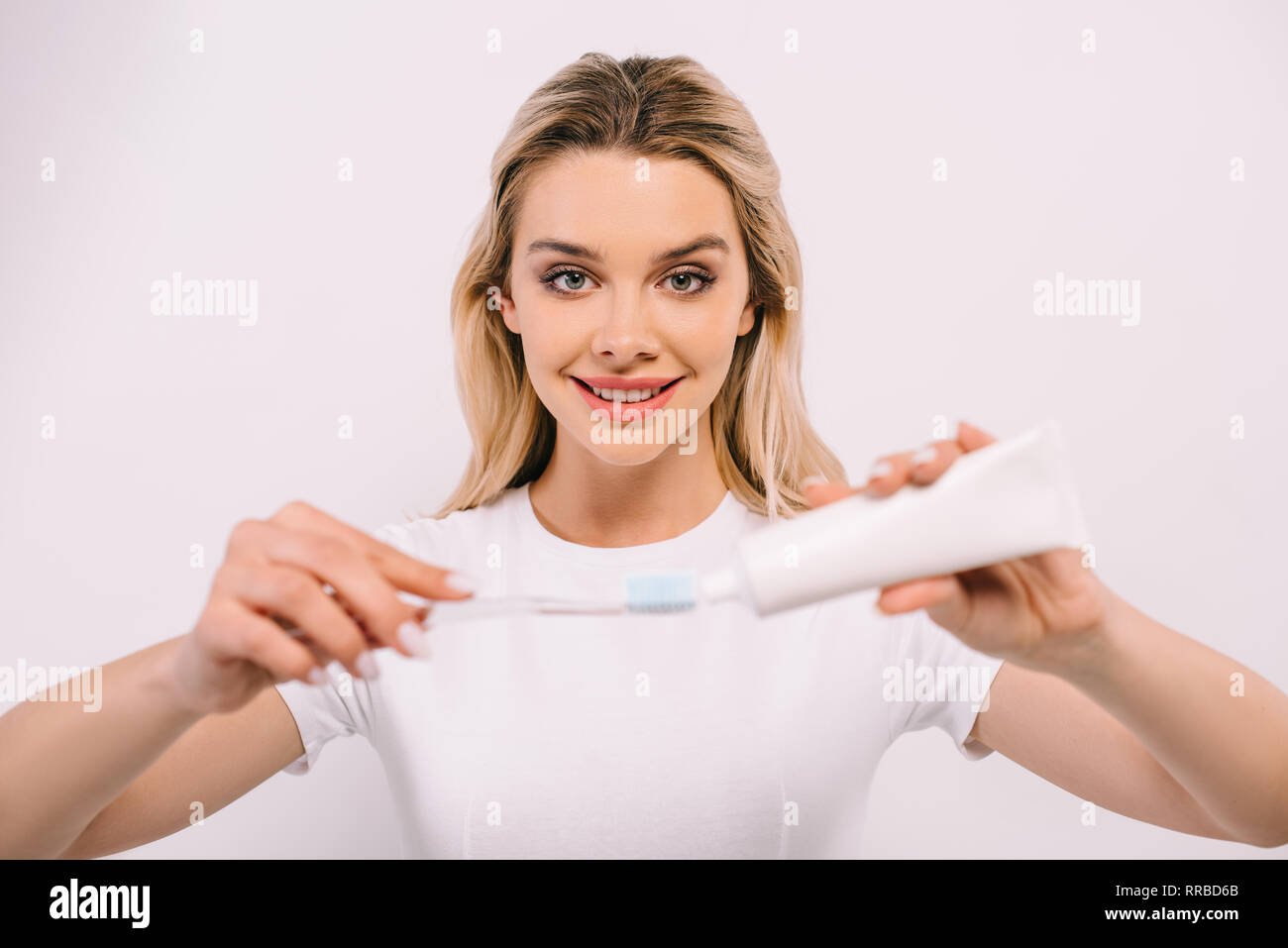 beautiful smiling woman putting toothpaste on toothbrush isolated on ...