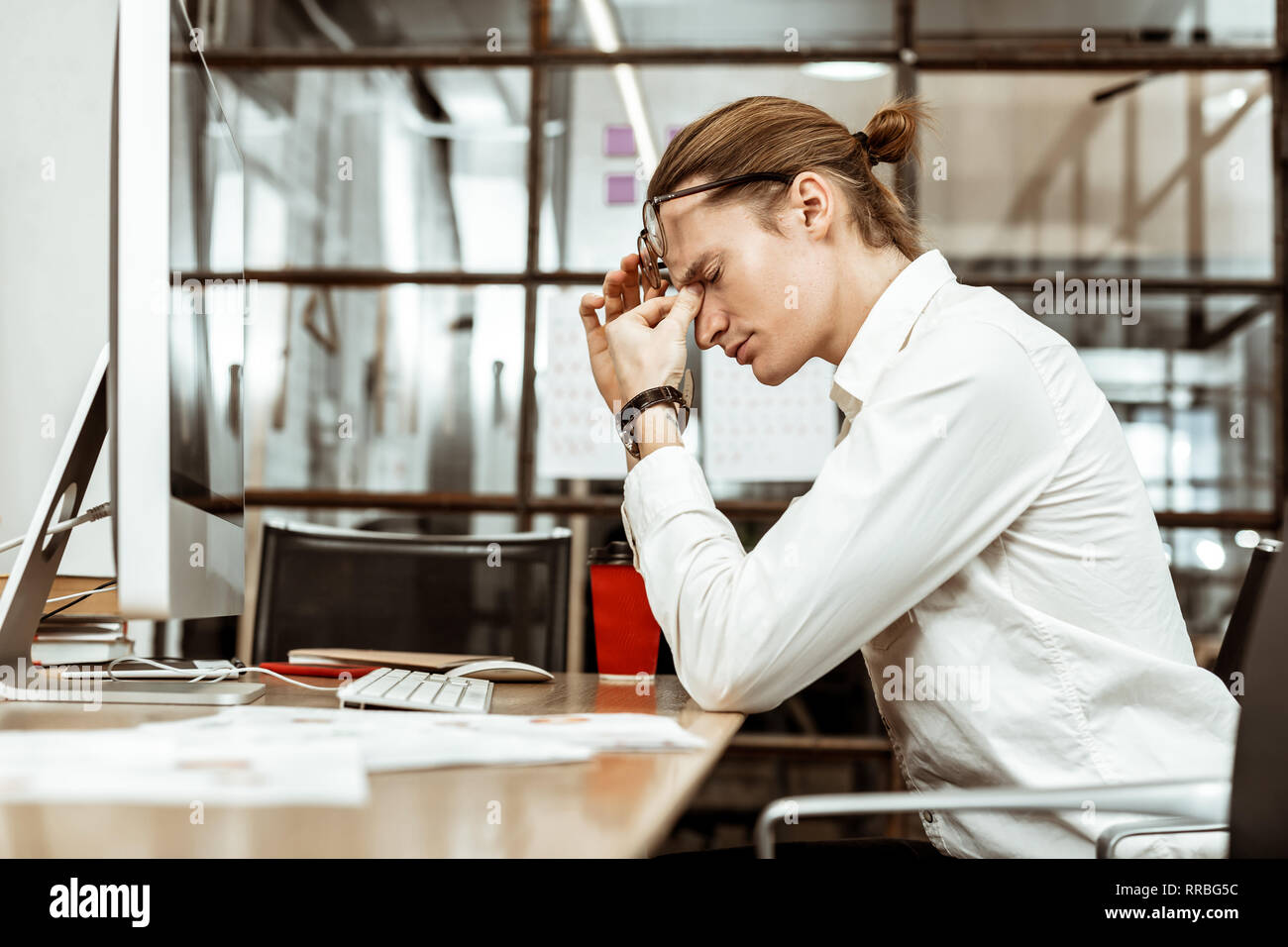 Nice young man holding a bridge of his nose Stock Photo - Alamy