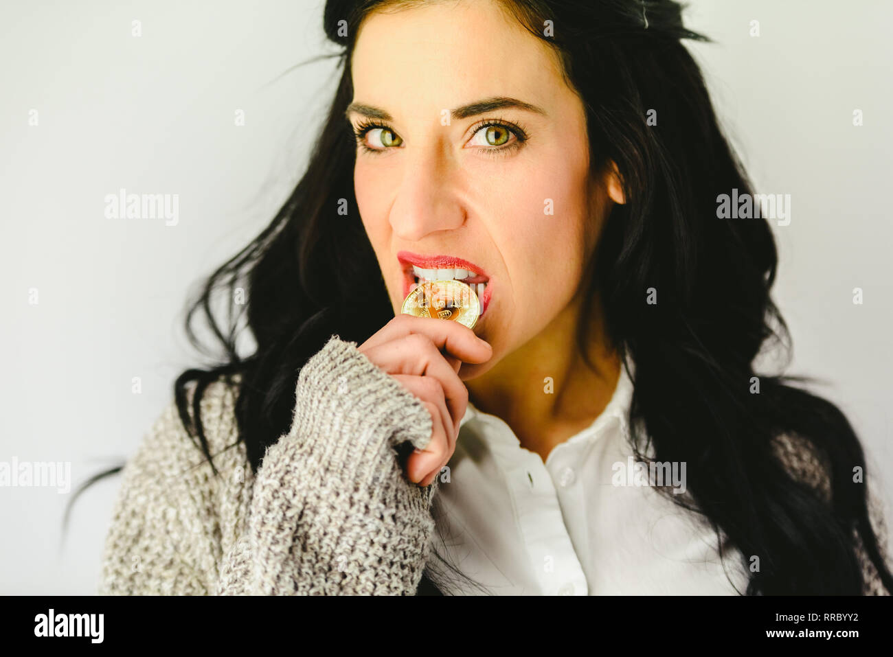 Aggressive woman biting a golden bitcoin coin isolated on white Stock ...