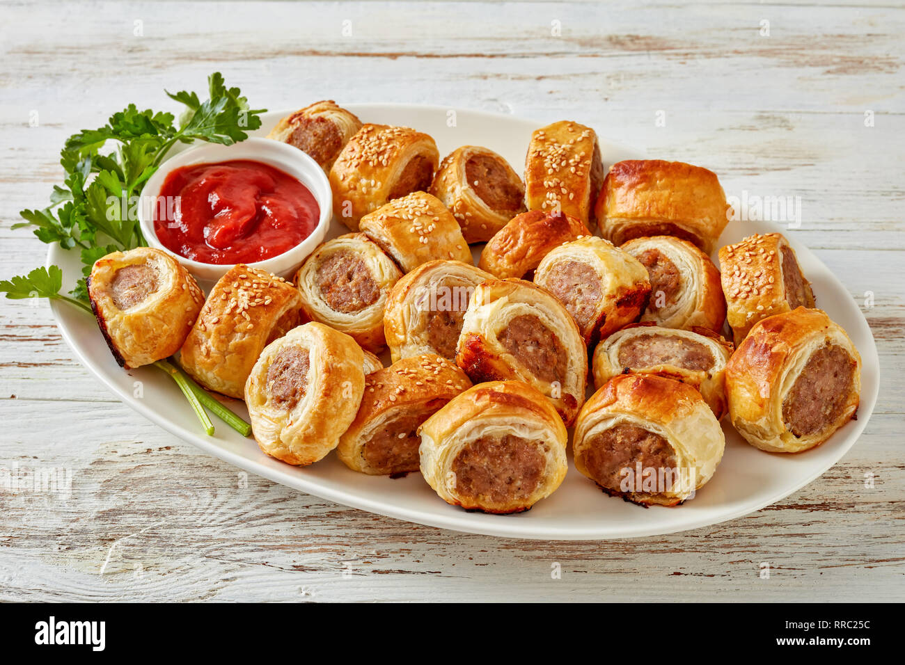 Puff pastry Sausage rolls with tomato sauce and parsley on a white ...