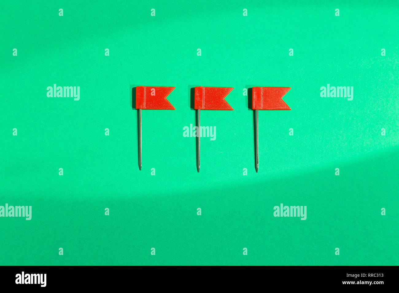 Three red little flag pins on a green background. View from above Stock ...