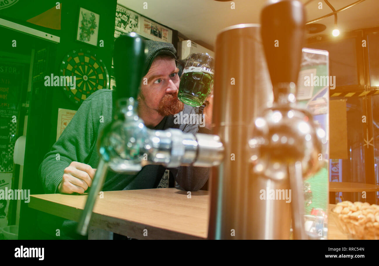 Crazy Irish guy holding mug of green beer in pub during St Patrick Day ...