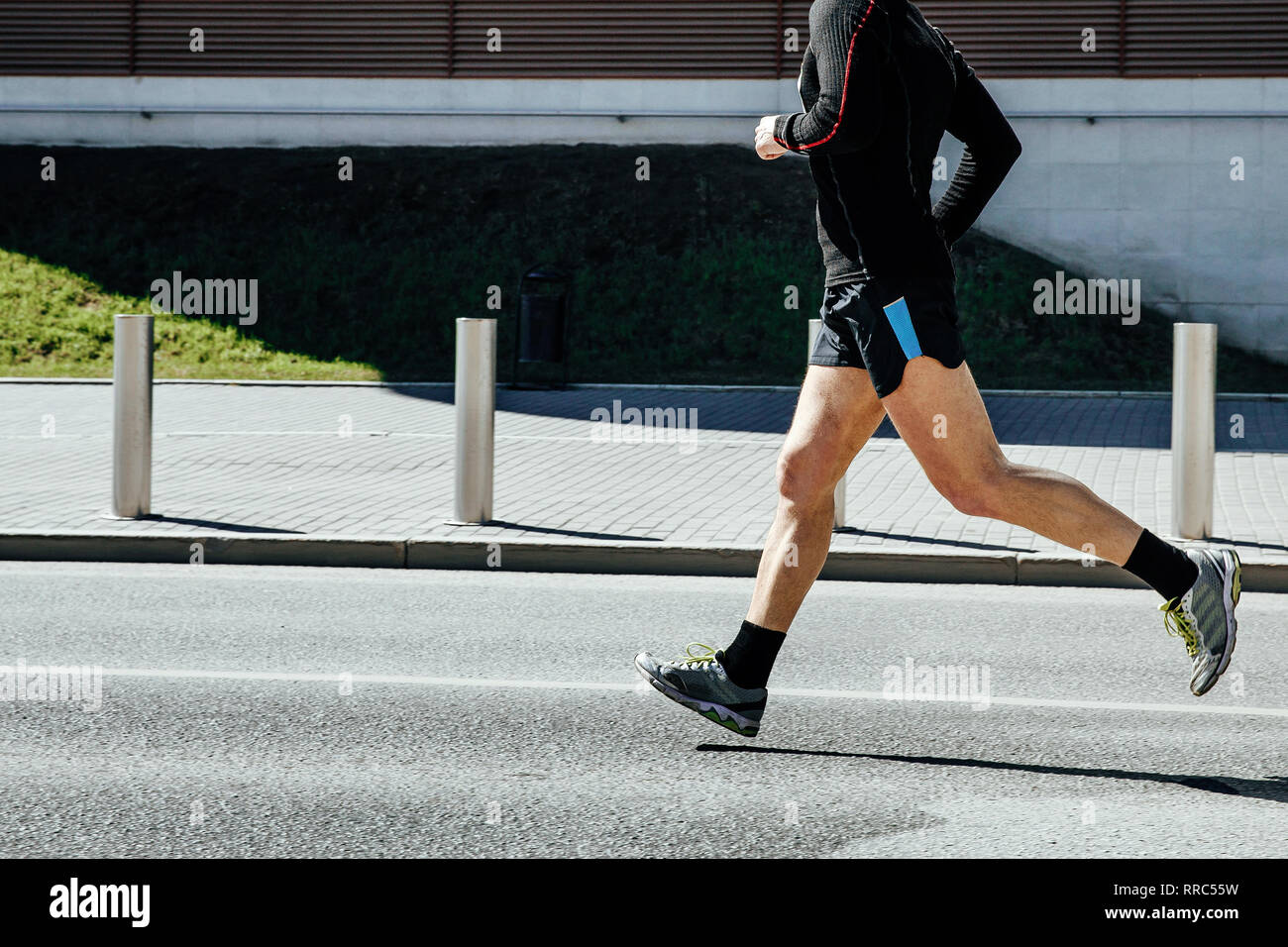 side view male runner in black sportswear running road in city Stock ...