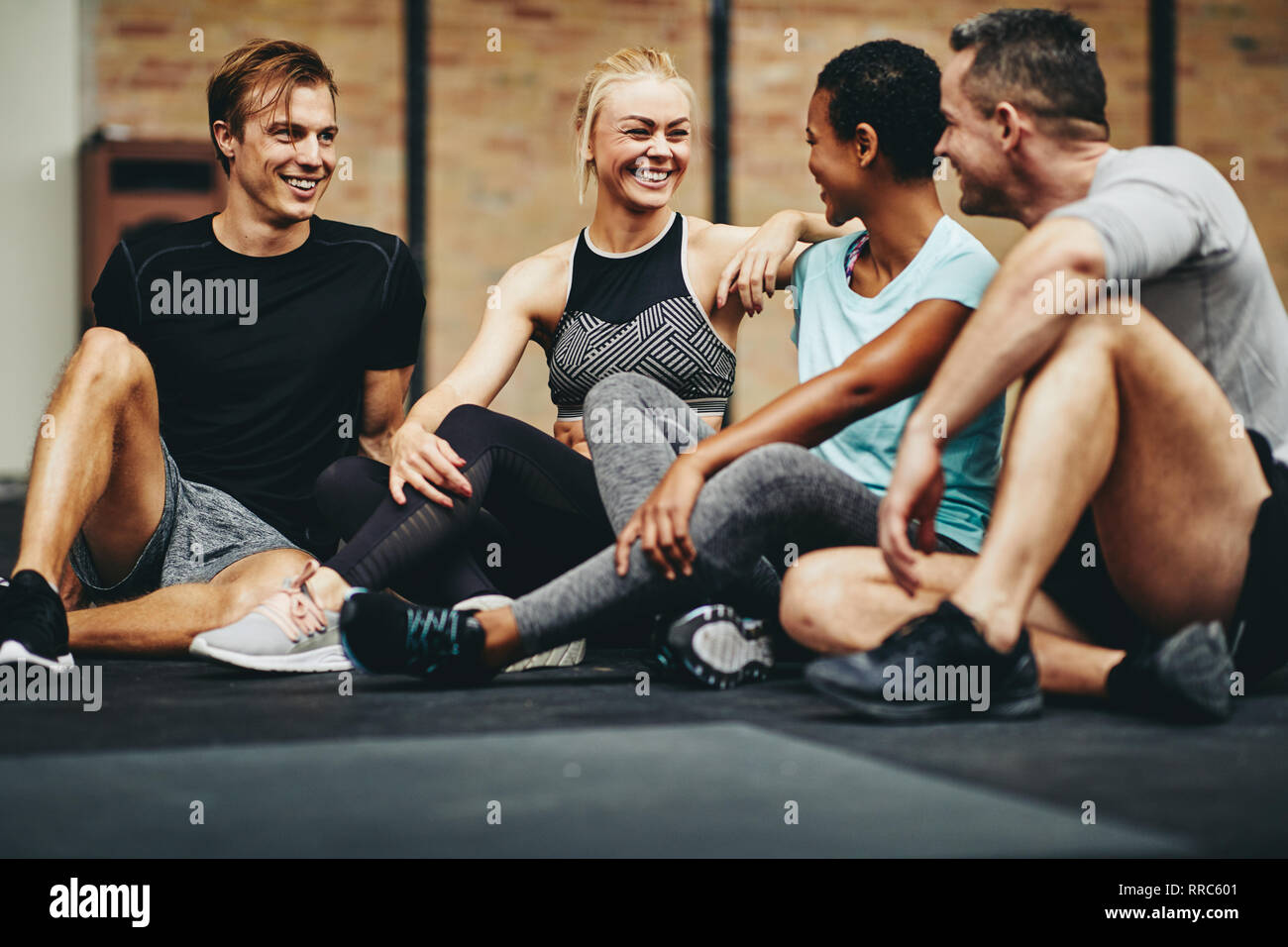 Diverse group of fit people in sportswear laughing while sitting on the ...