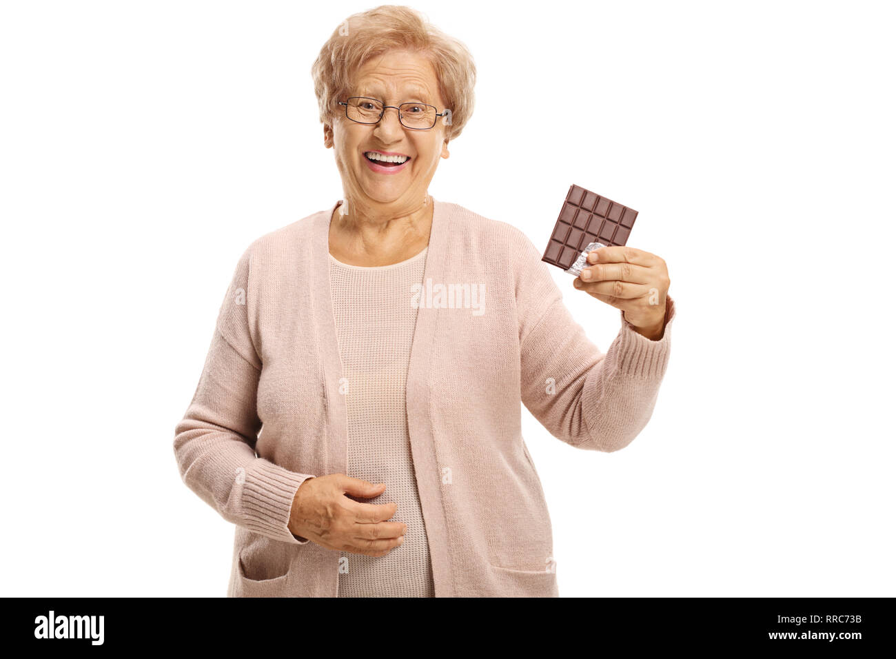 Cheerful senior woman holding a chocolate bar and smiling at the camera ...