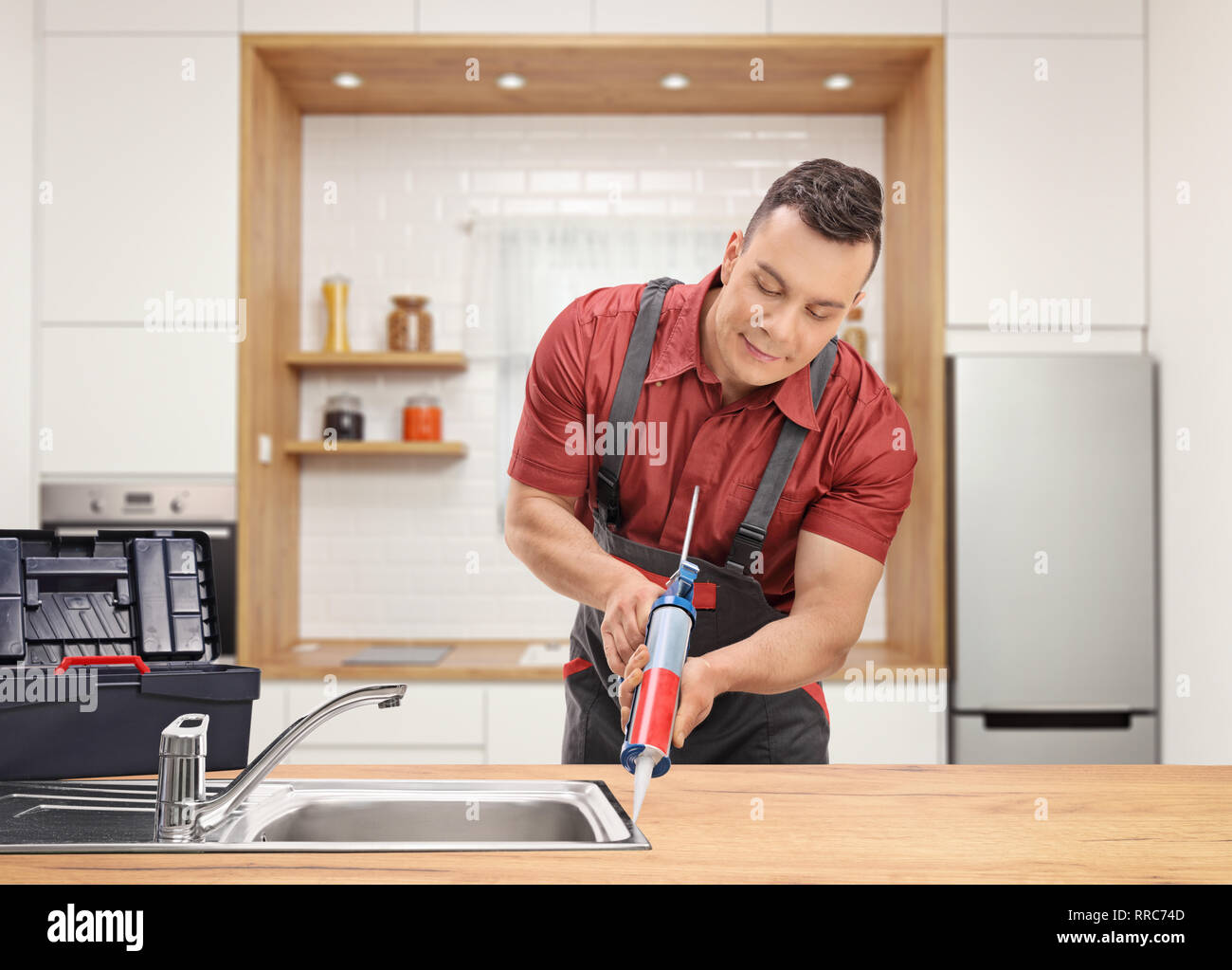 Plumber using a silicone tube on a sink inside a modern kitchen Stock ...