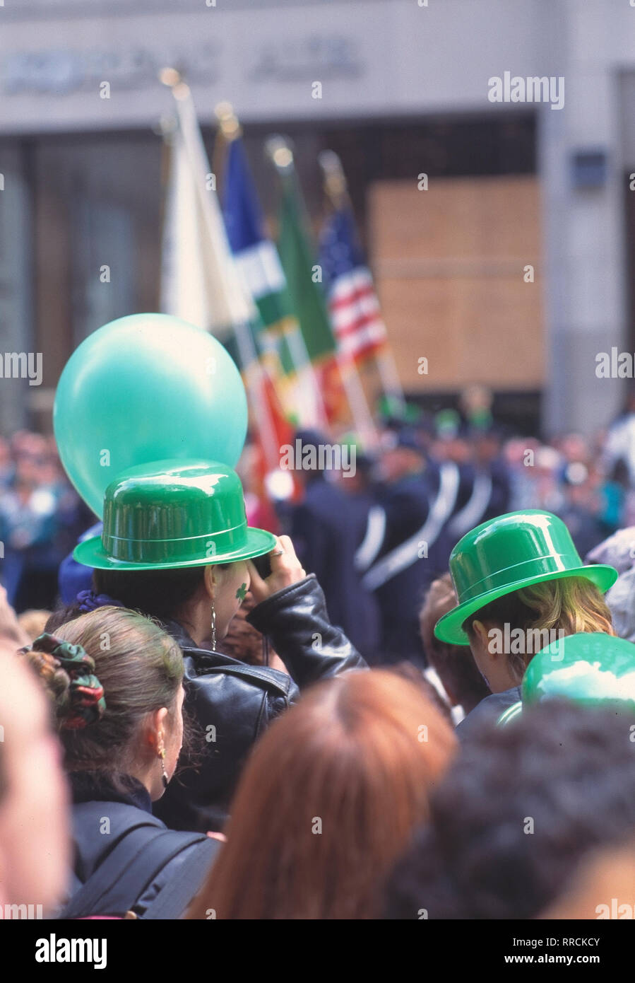 Happy people with green bowler hats and balloons cheering at St ...