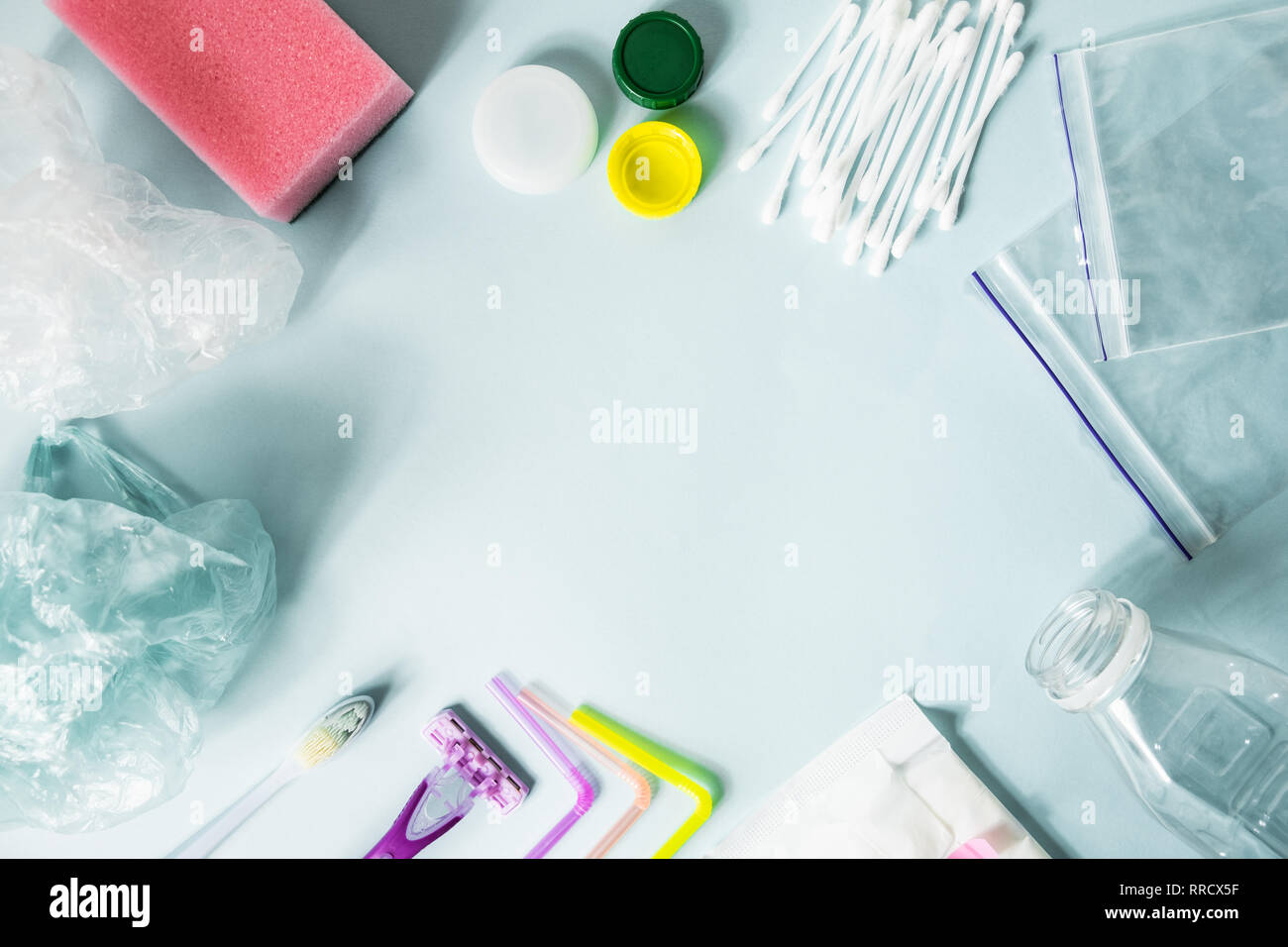 Disposable plastic items of every day use on blue background, top view ...