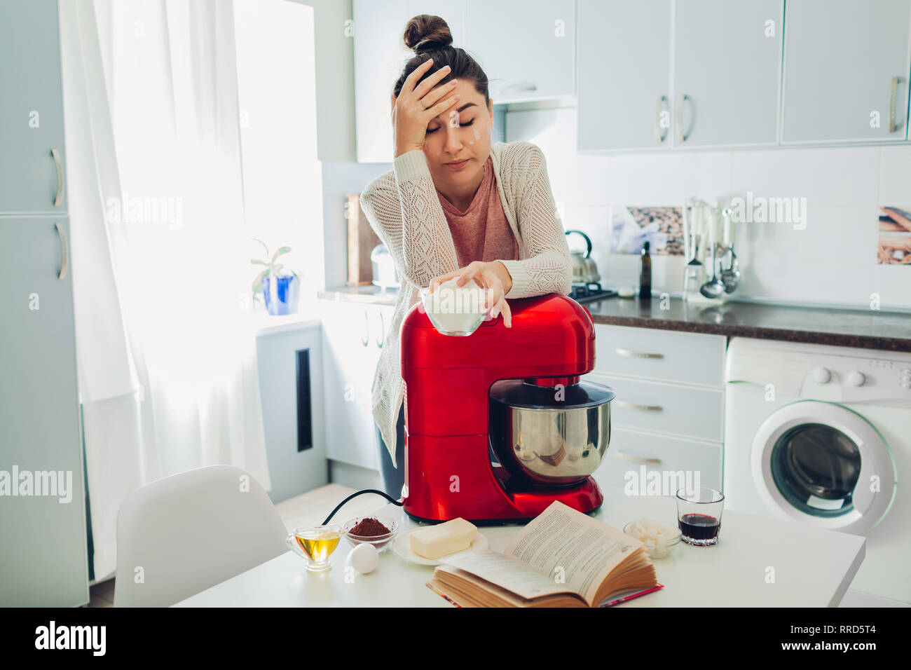 Tired housewife leaning on food processor while cooking on kitchen at ...