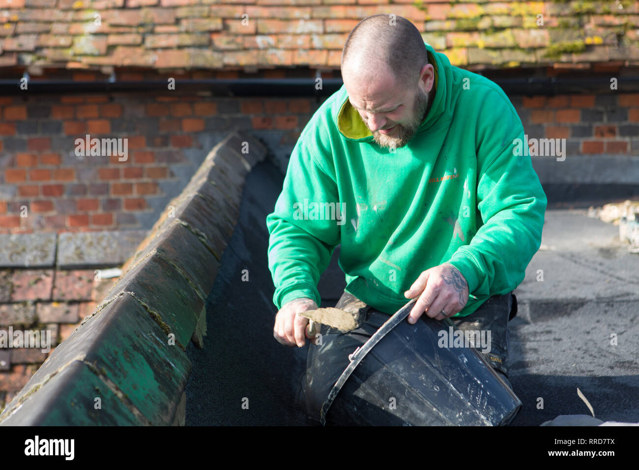 Workers repairing flat roof over garage on heritage house Stock Photo - Alamy