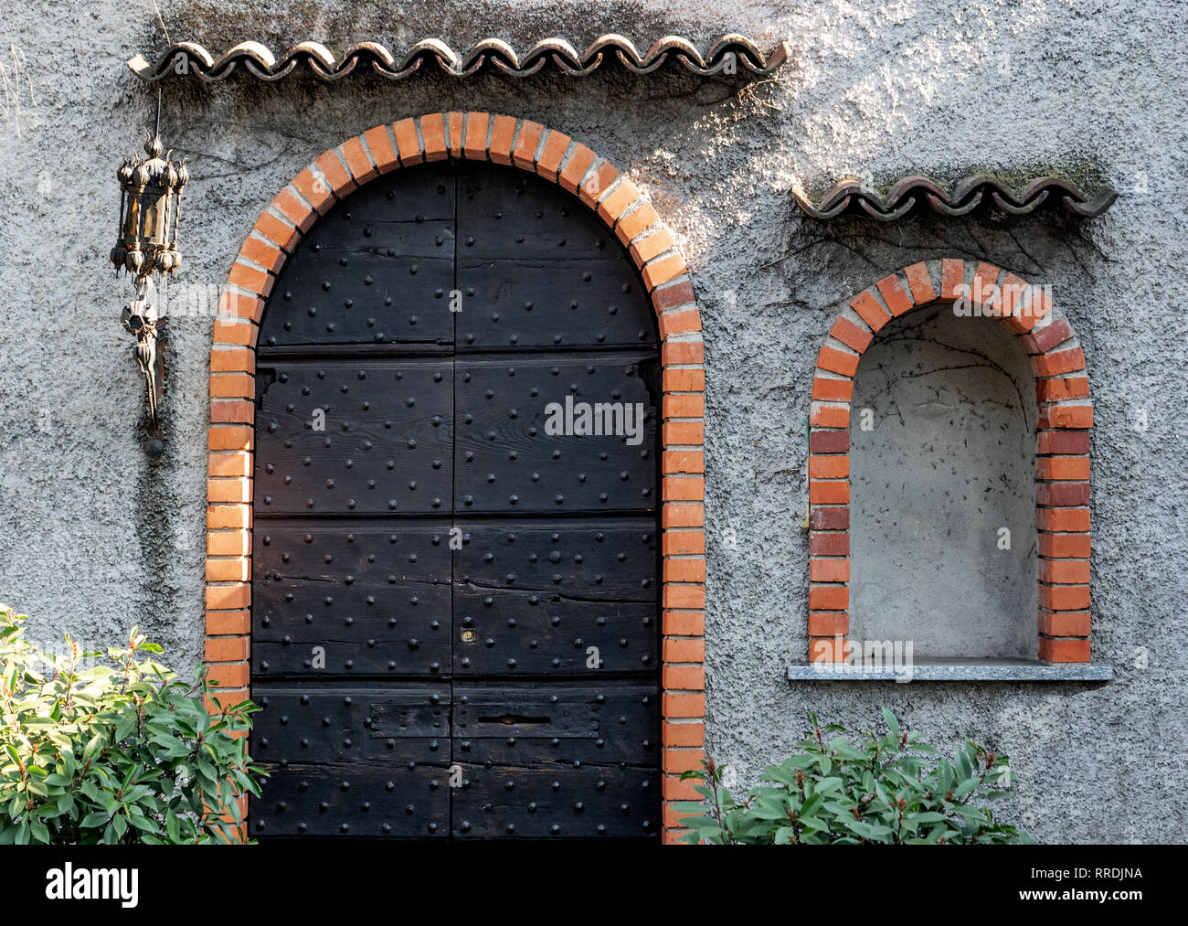 red brick arch with wooden door with studs and ancient lantern Stock ...