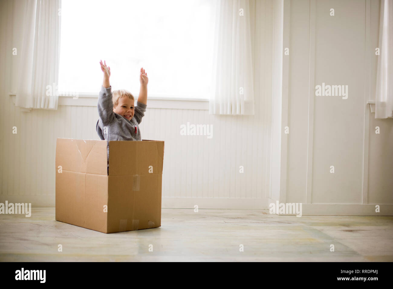 Young boy sitting inside a cardboard box Stock Photo - Alamy