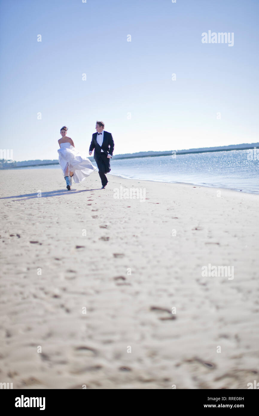 Bride and groom running along the beach Stock Photo - Alamy