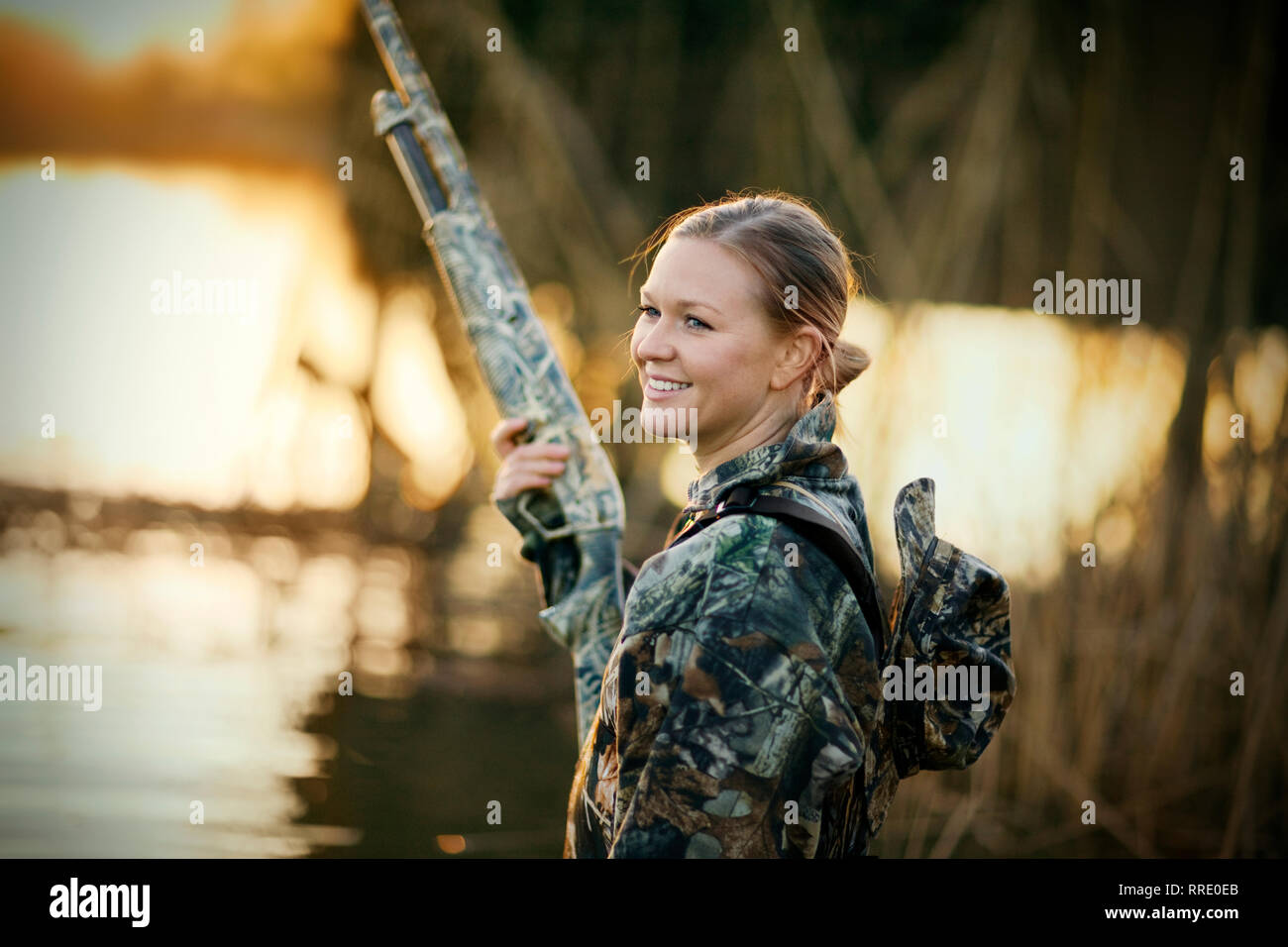 Young adult woman duck shooting by a lake Stock Photo - Alamy