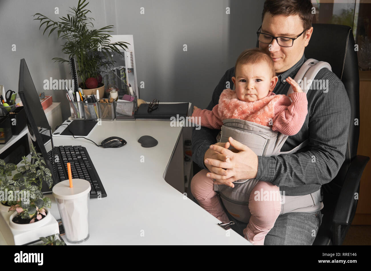 Man father with baby in carrier working at office or home with computer ...