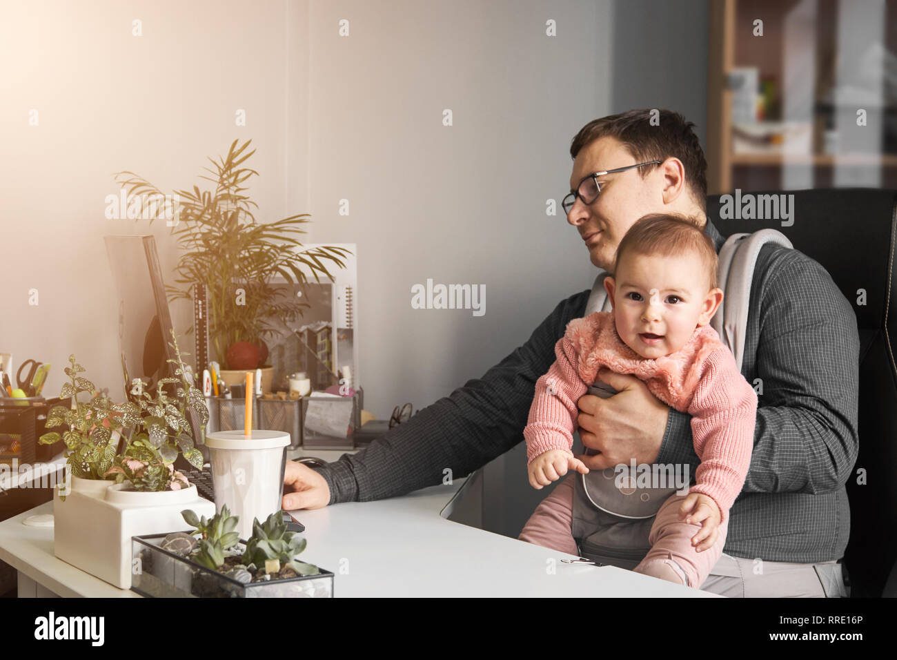 Man father with baby in carrier working at office or home with computer ...