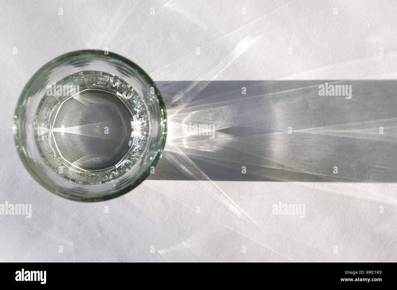 Glass beaker from which padajet sharp shadow, stands on a white ...