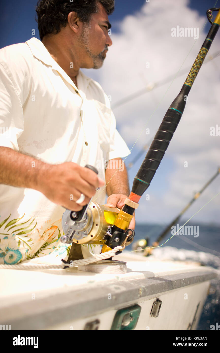 A man fishing off the side of his boat Stock Photo - Alamy