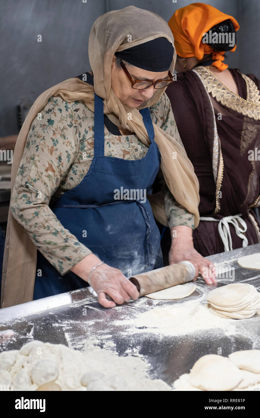 A woman volunteer in a langar, A Sikh temple kitchen, prepares roti, a ...