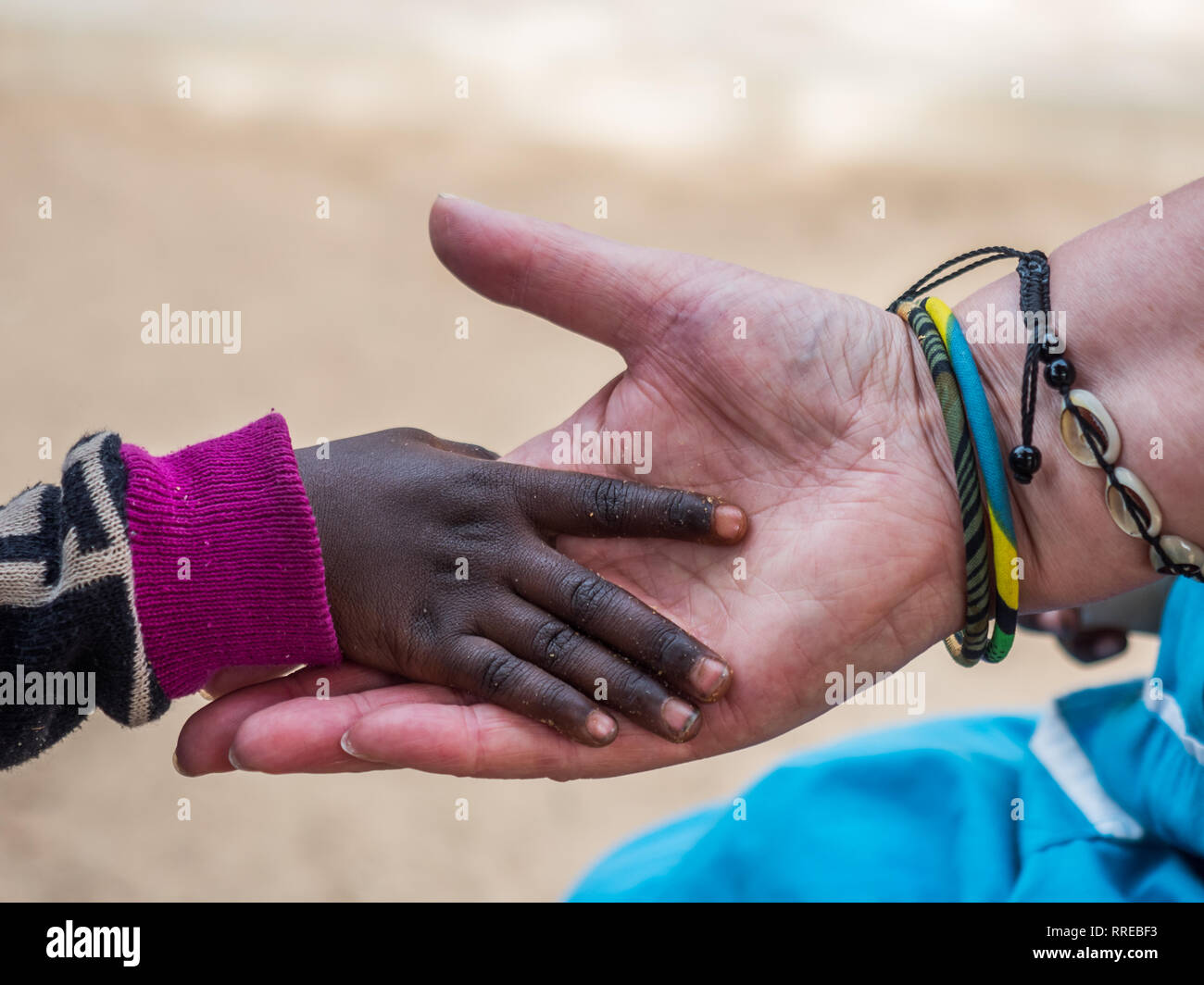 African child is touching hand of white woman. Diversity concept ...
