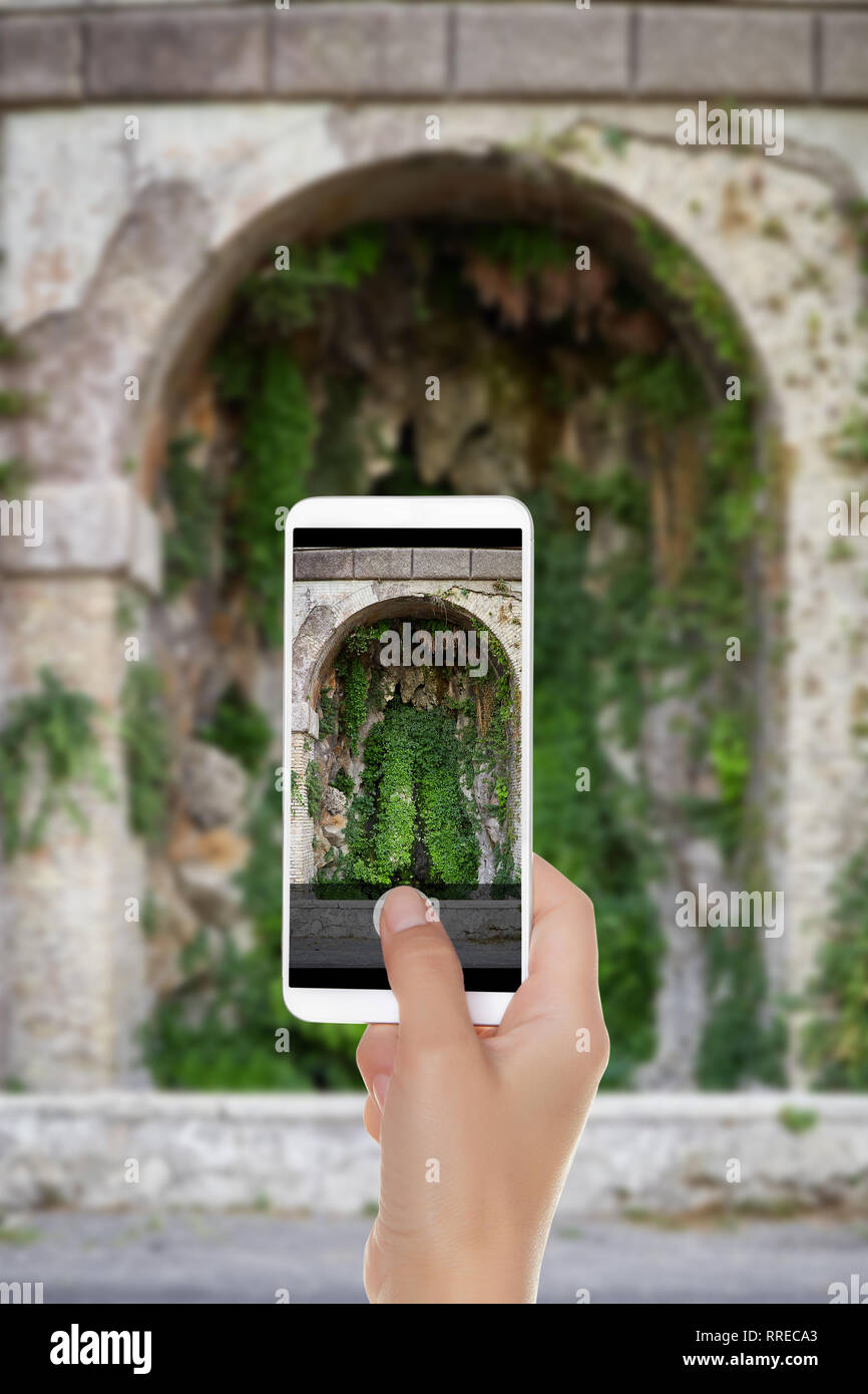 A man is making a photo of a small cave overgrown with ivy near ...