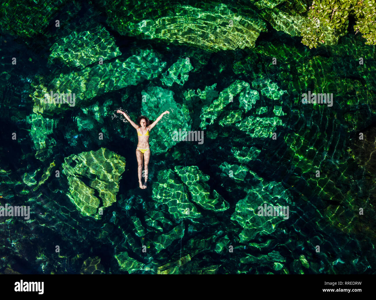Overhead shot of a attractive young brunette woman in a bikini floating ...