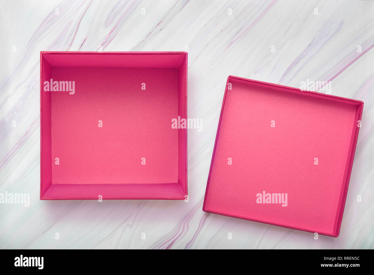Flat lay of empty pink gift box with lid on natural marble texture ...