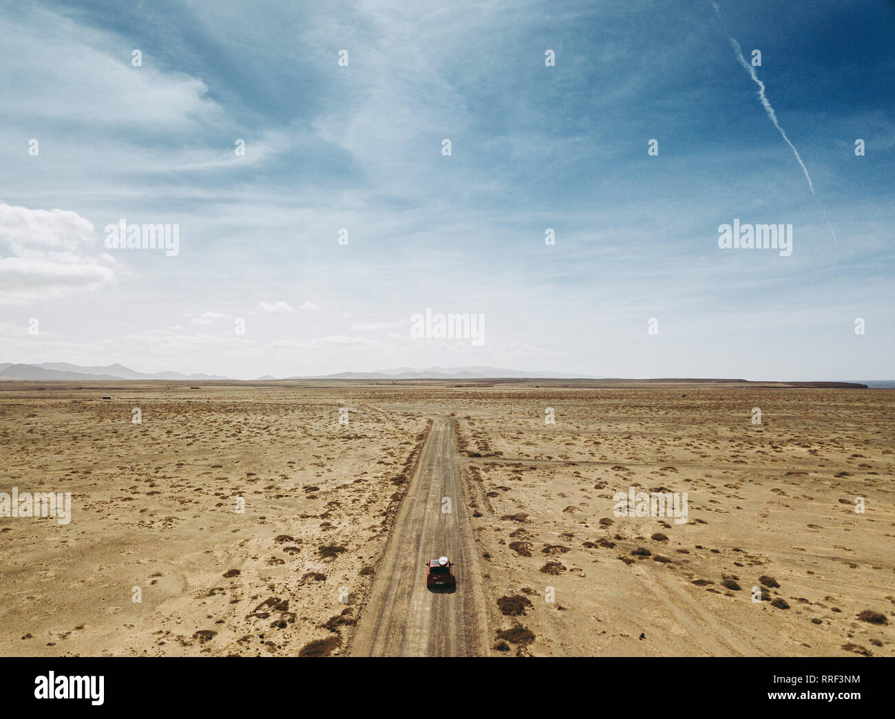 Aerial view of empty desert land with car driving on remote roadway ...