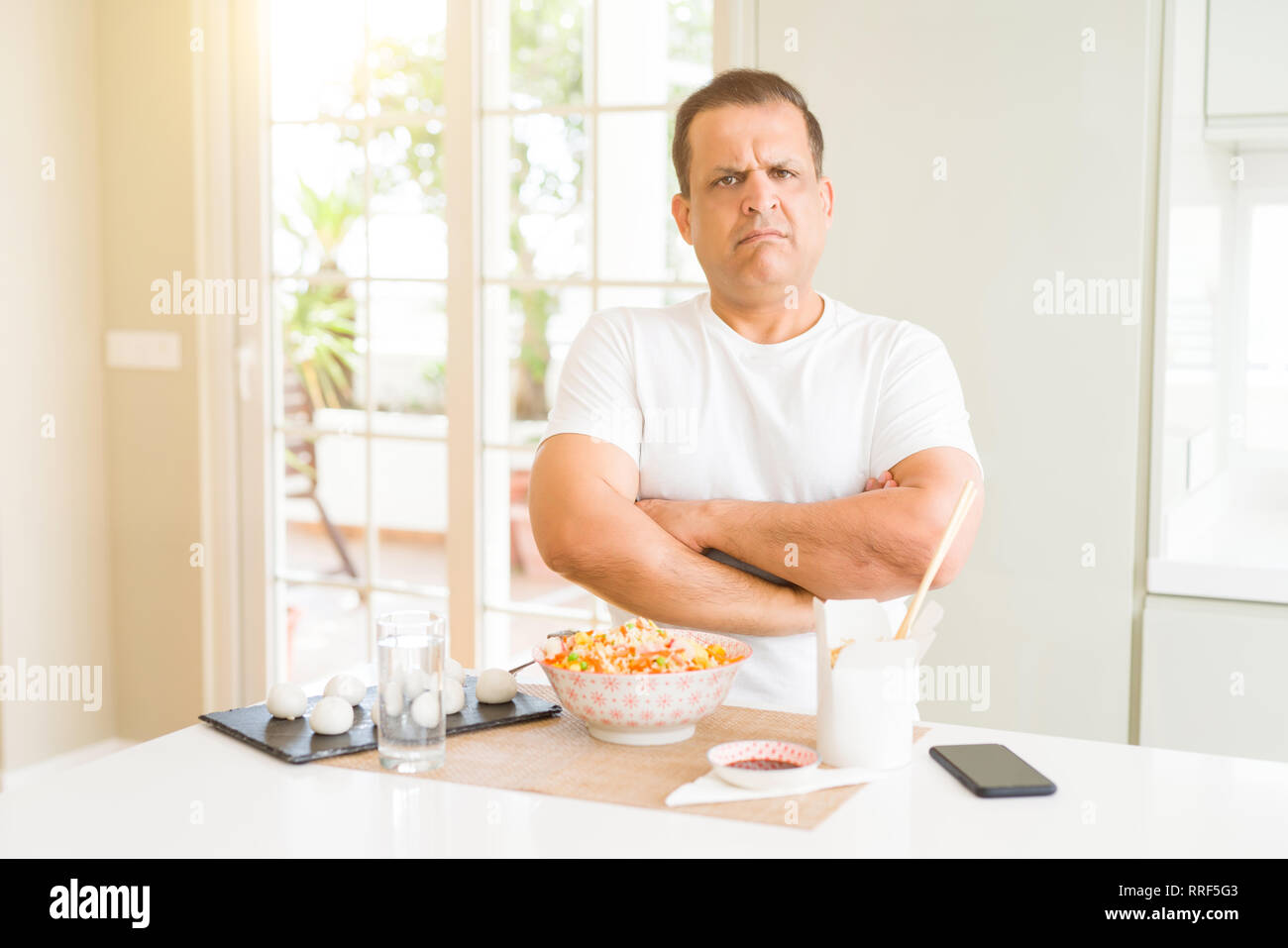 Middle age man eating asian food with chopsticks at home skeptic and ...