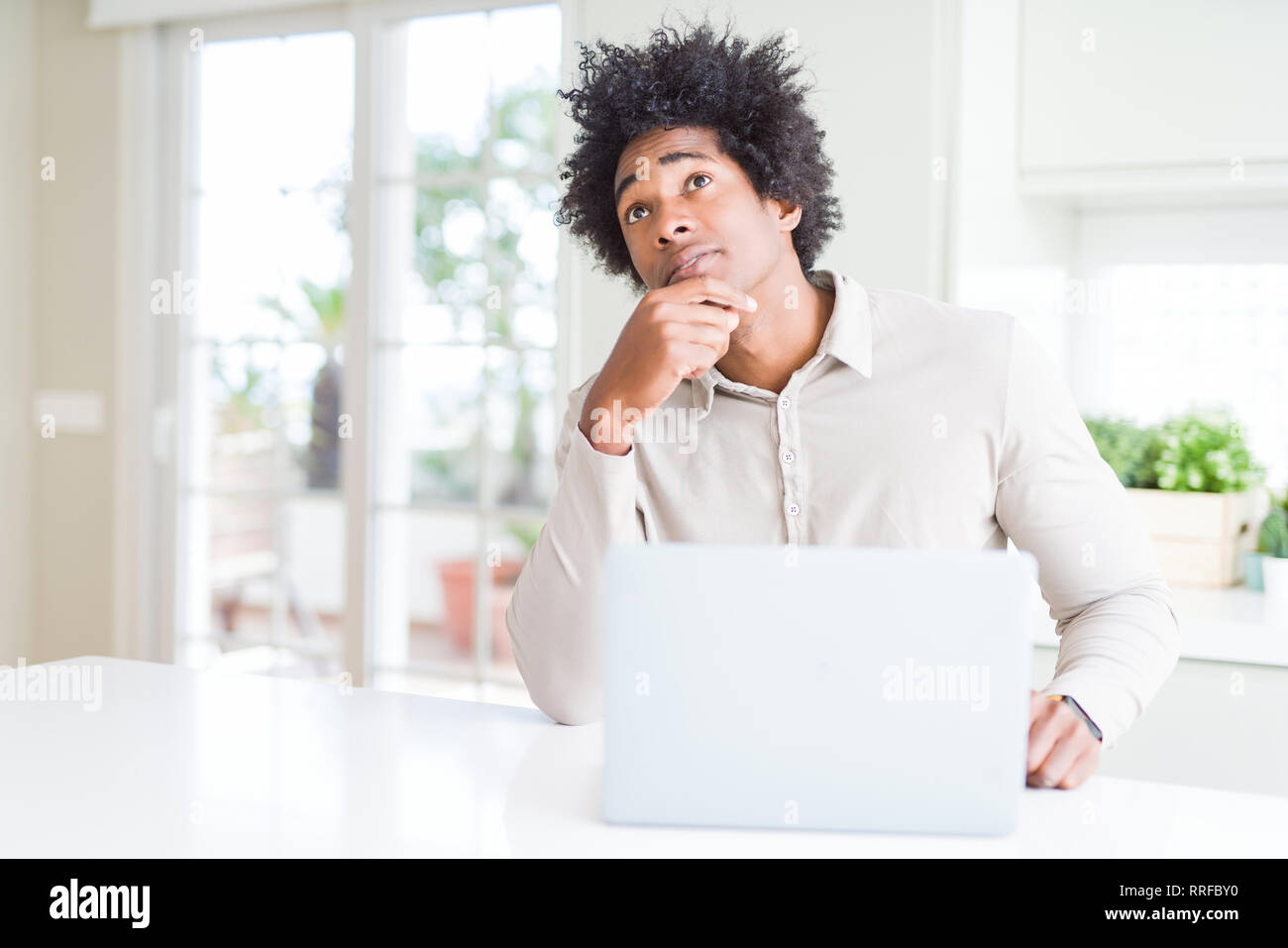 African American man working using laptop serious face thinking about ...