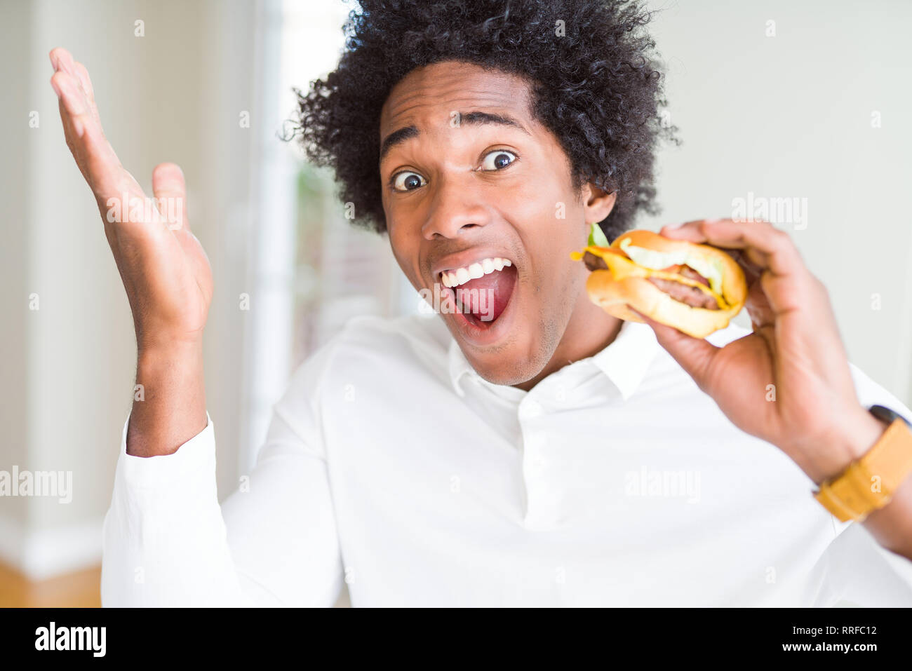 African American hungry man eating hamburger for lunch very happy and ...