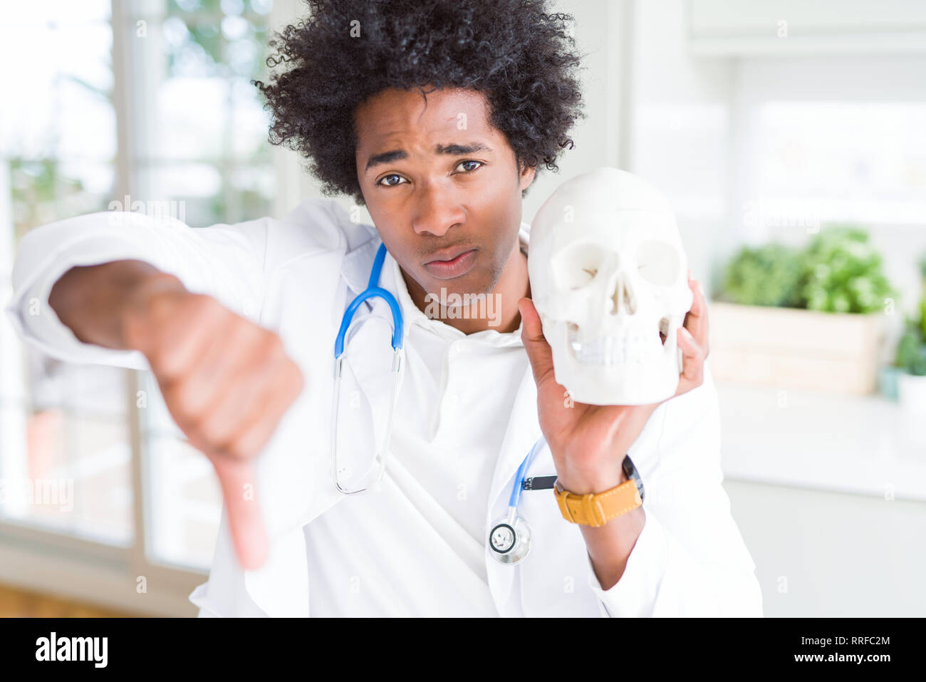 African American doctor man holding skull with angry face, negative ...