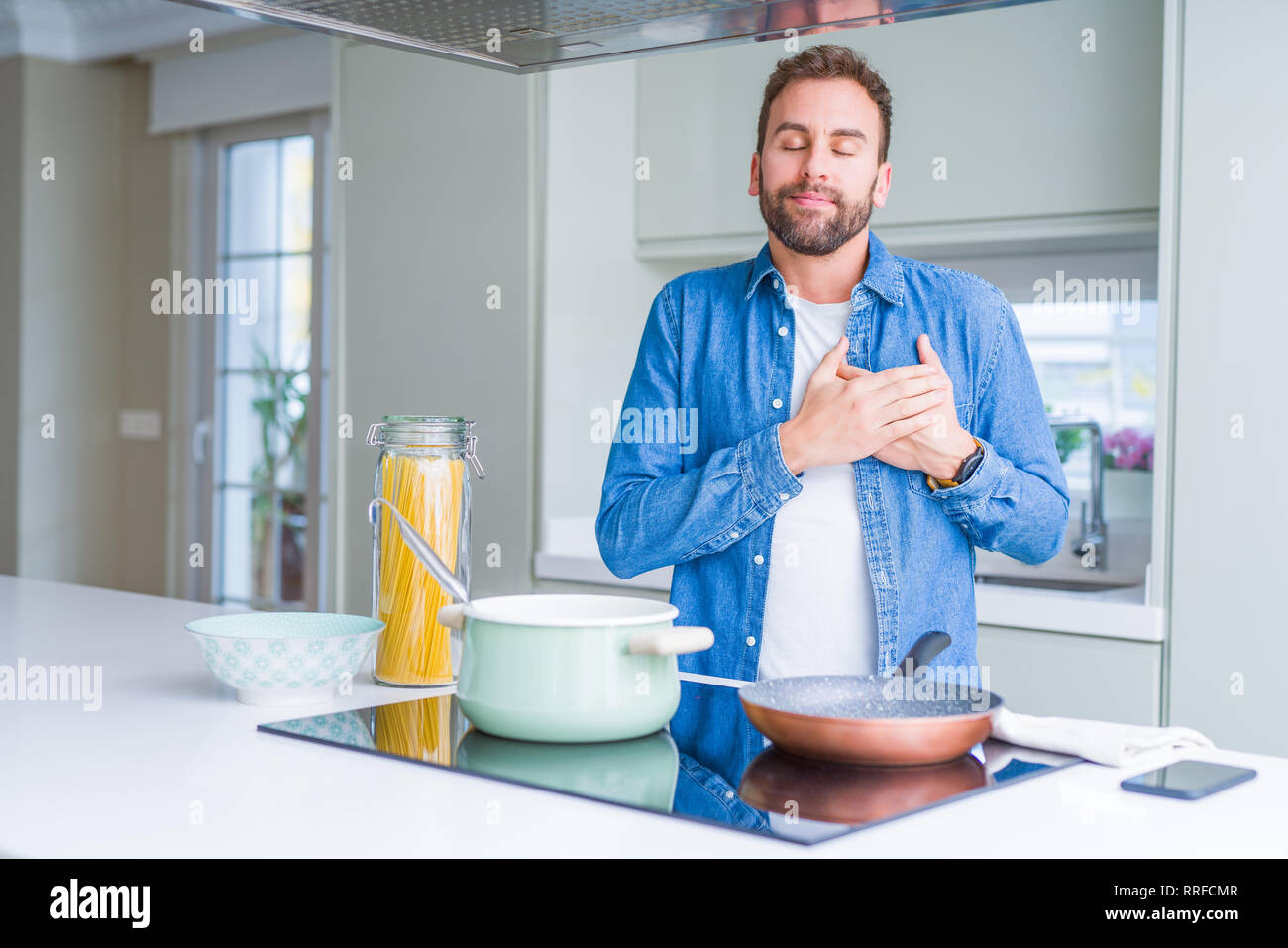 Handsome man cooking italian spaghetti pasta at the kitchen smiling ...