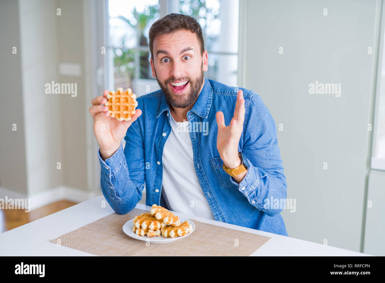 Handsome man eating sweet Belgian pancakes very happy and excited ...