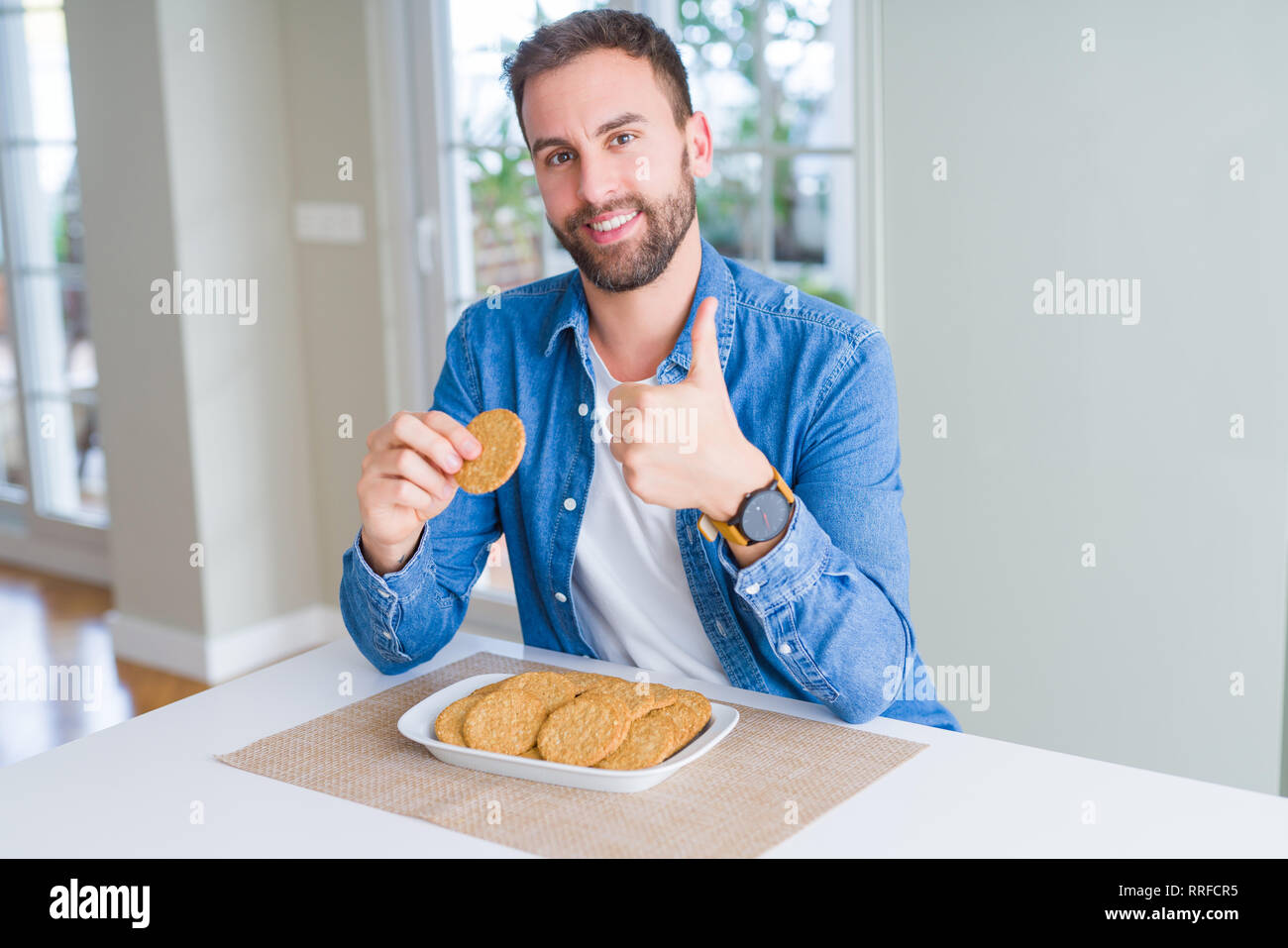 Handsome man eating healthy whole grain biscuit happy with big smile ...