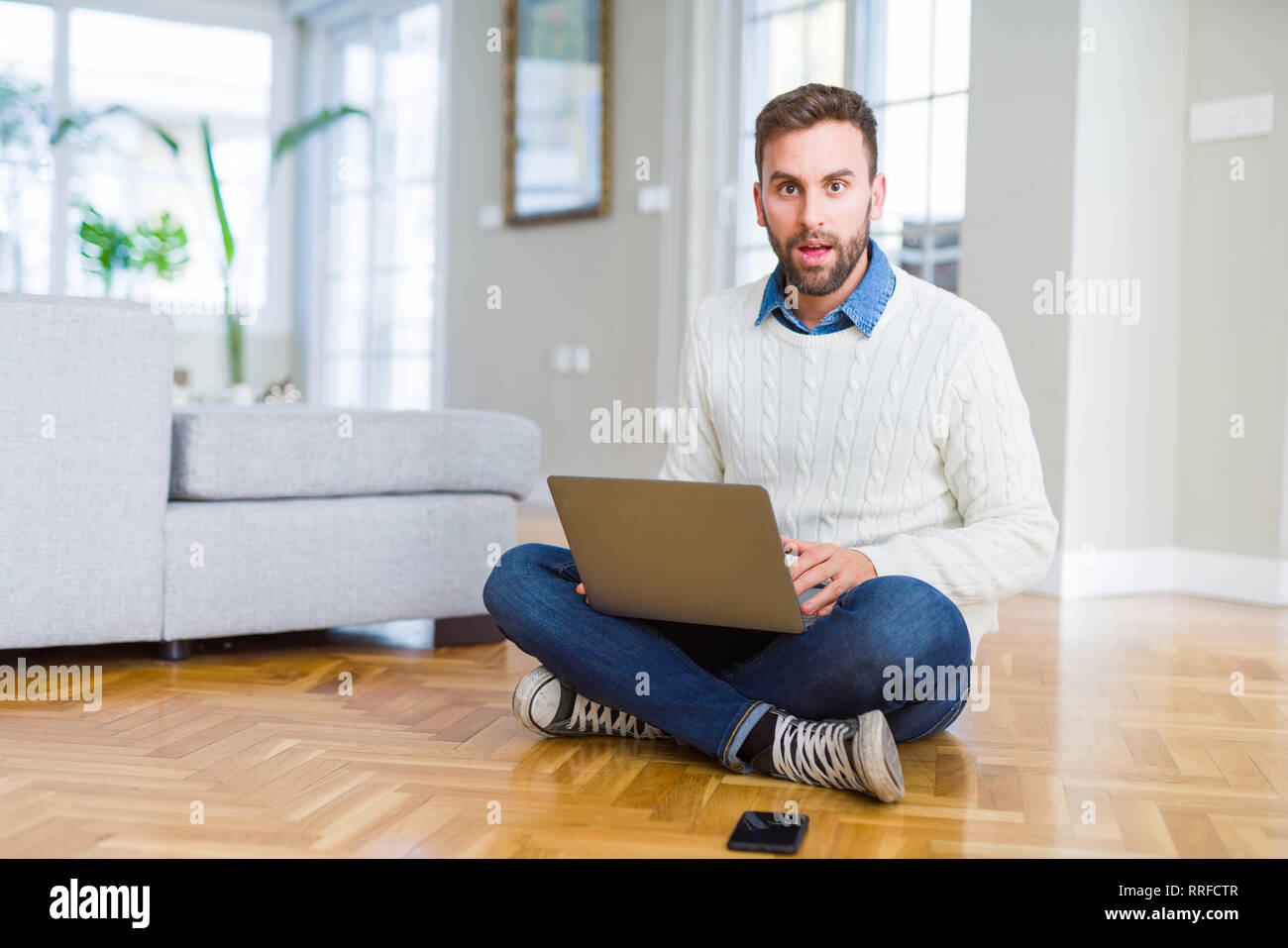 Handsome man wearing working using computer laptop afraid and shocked ...