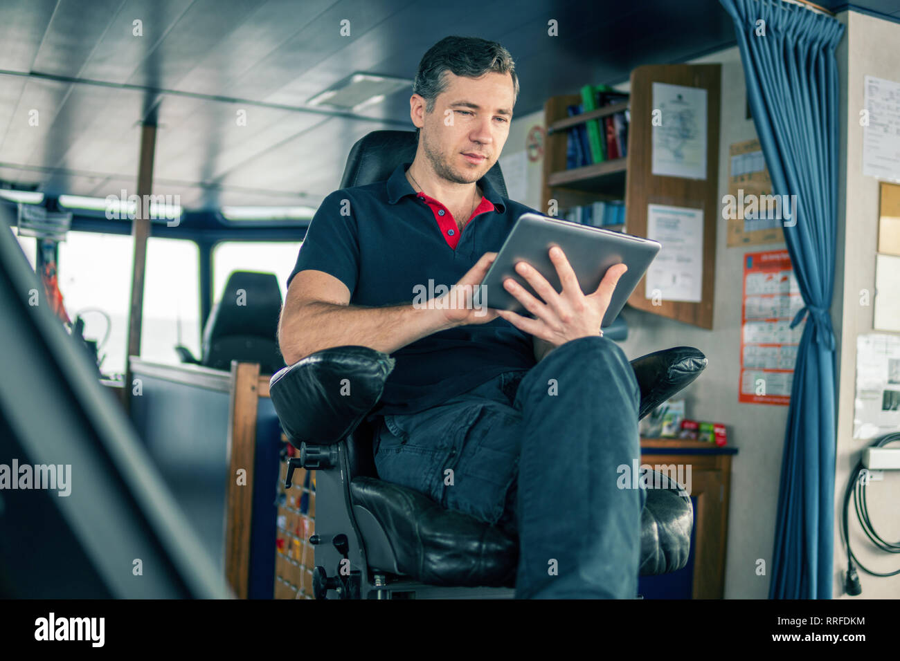 chief officer on navigation bridge watching digital tablet Stock Photo ...
