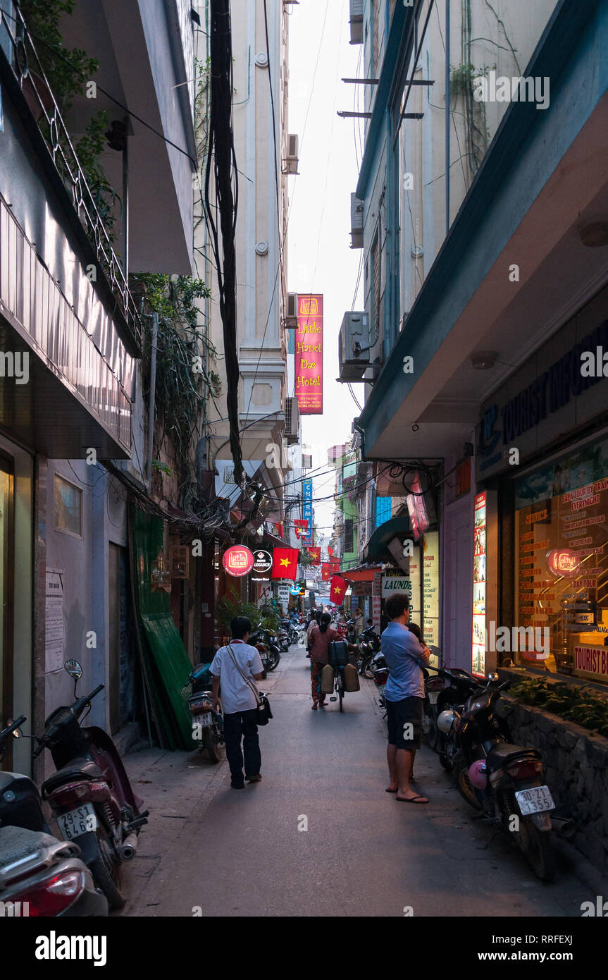 A narrow alley lined with shops and restaurants as people walk past ...