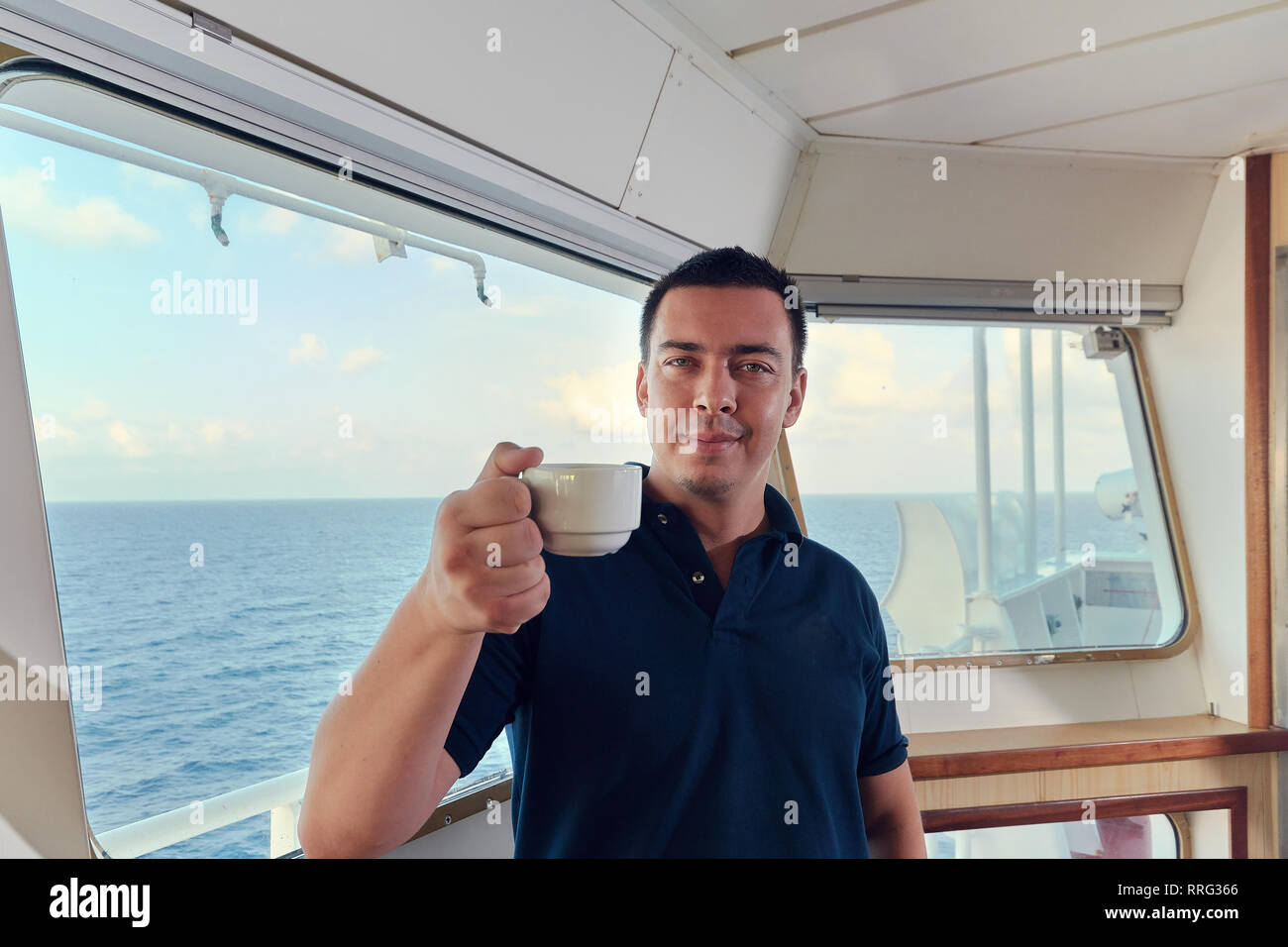Navigation offcier Pilot on the bridge of a ship underway with cup of ...