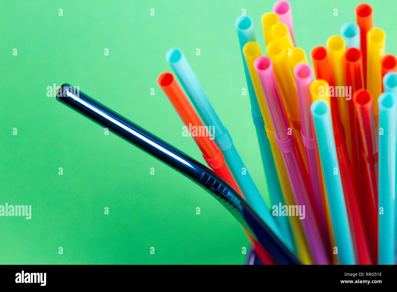 Stainless steel reusable drinking straw with plastic straws on green ...