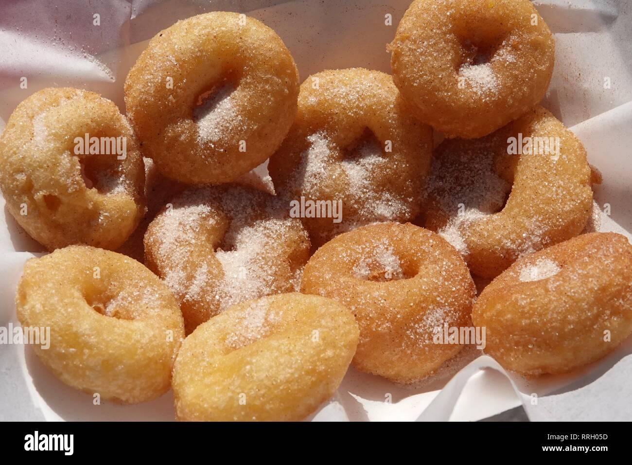 A group of powdered mini donuts in a basket covered in powder Stock ...