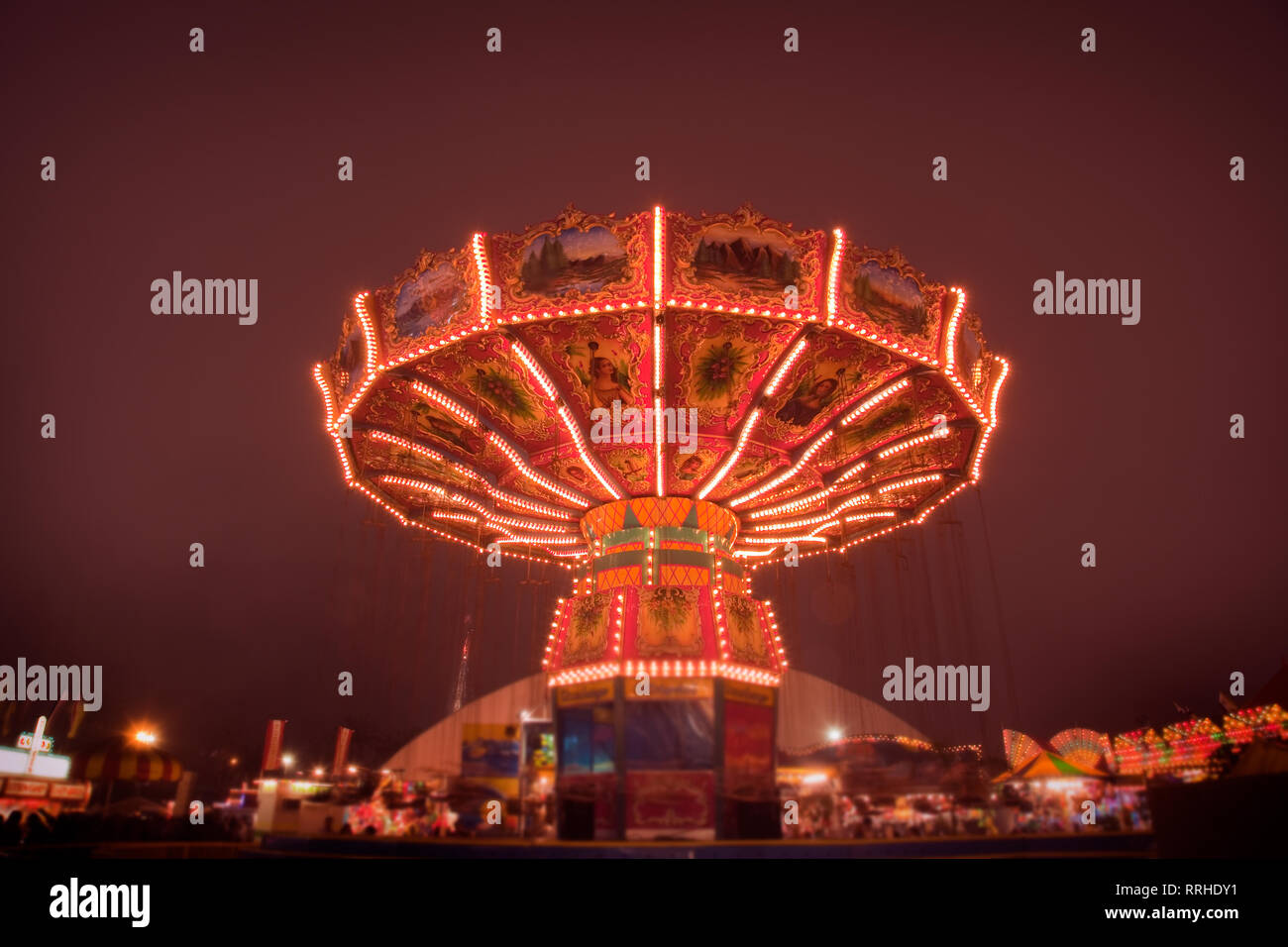 View looking up at the carousel swing ride. Carnival Midway at night ...