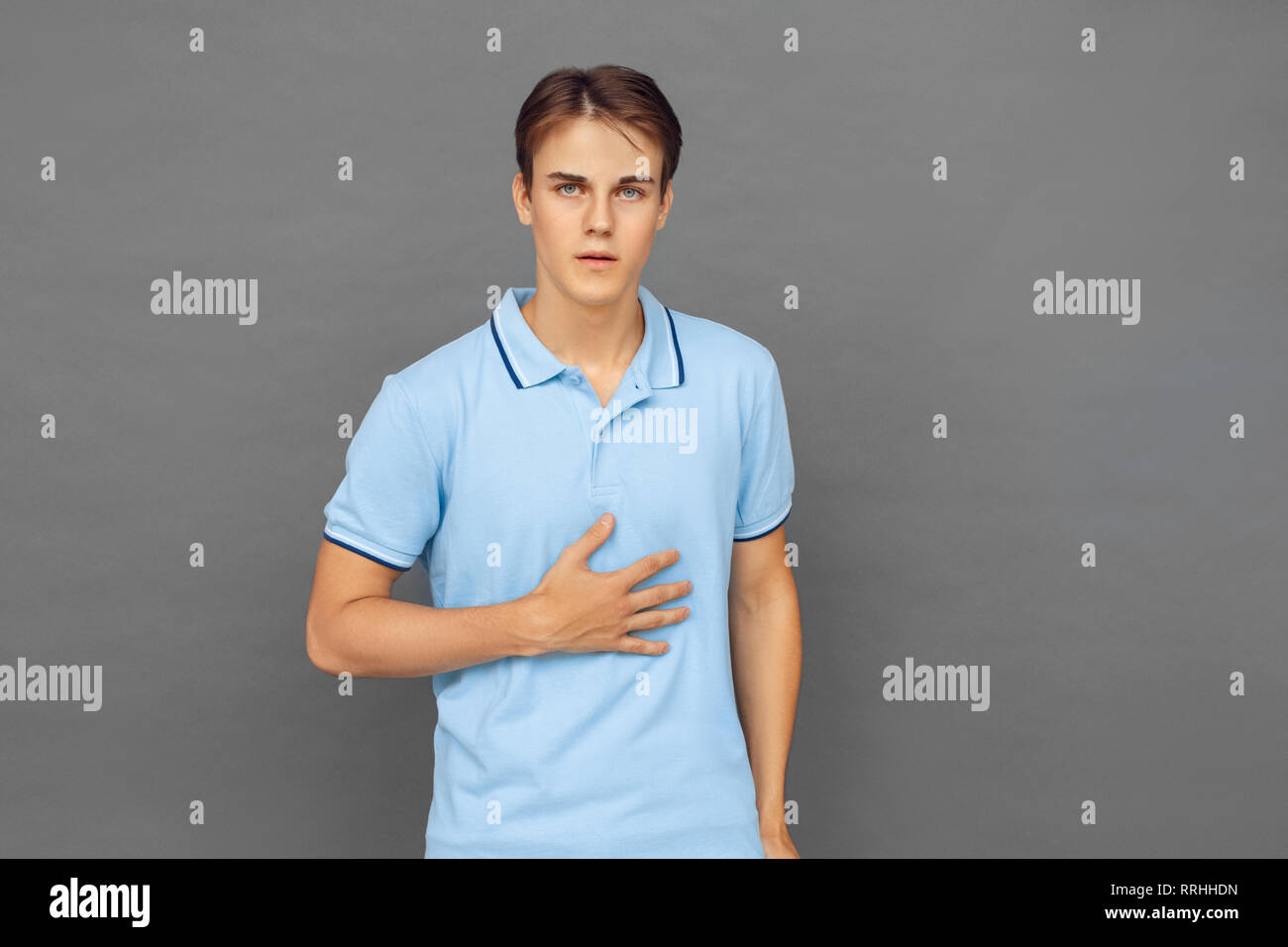 Freestyle. Teenager boy standing isolated on grey touching chest ...