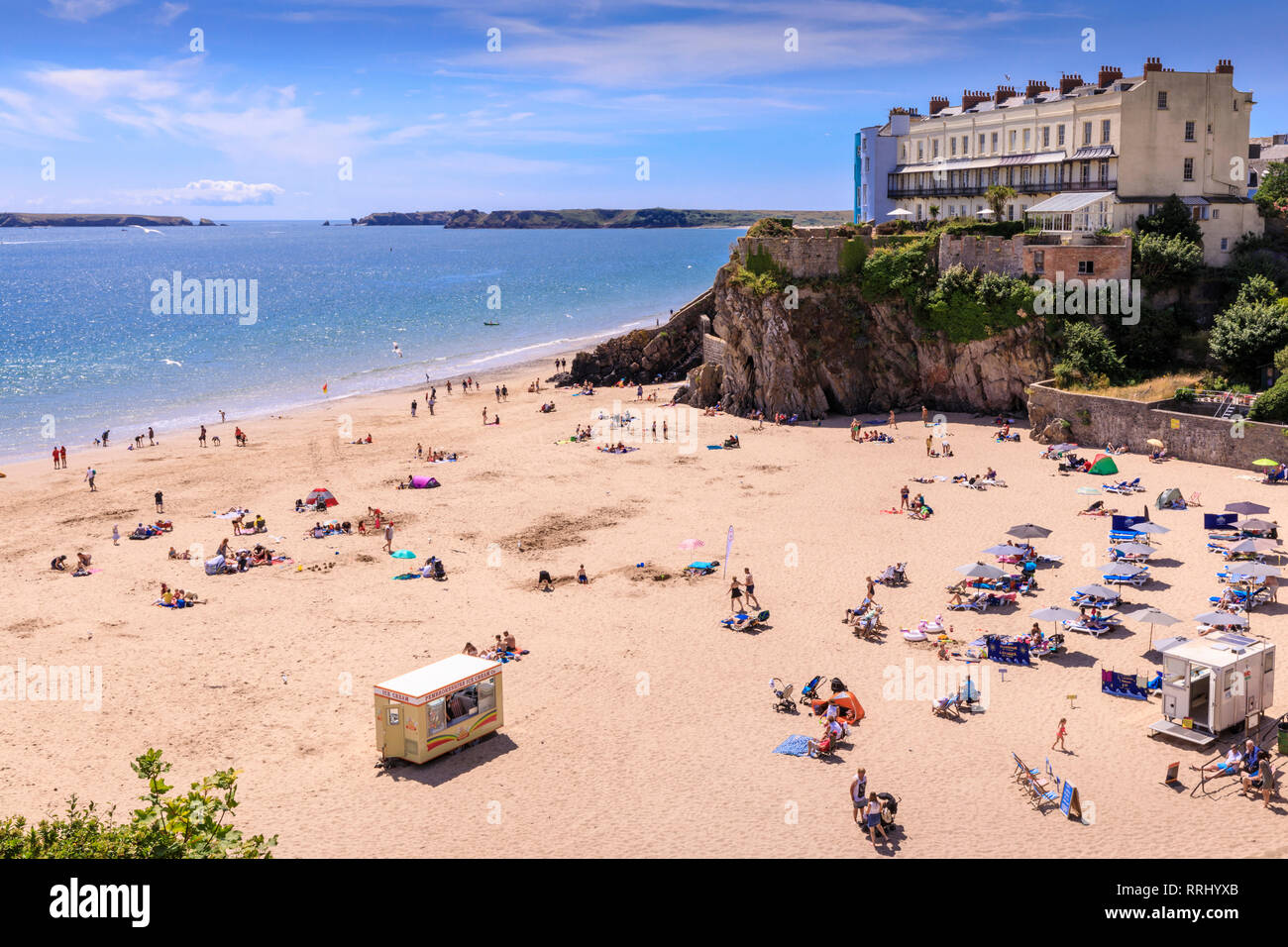 Castle Beach, historic houses above the cliffs, sunbathers on a sunny ...