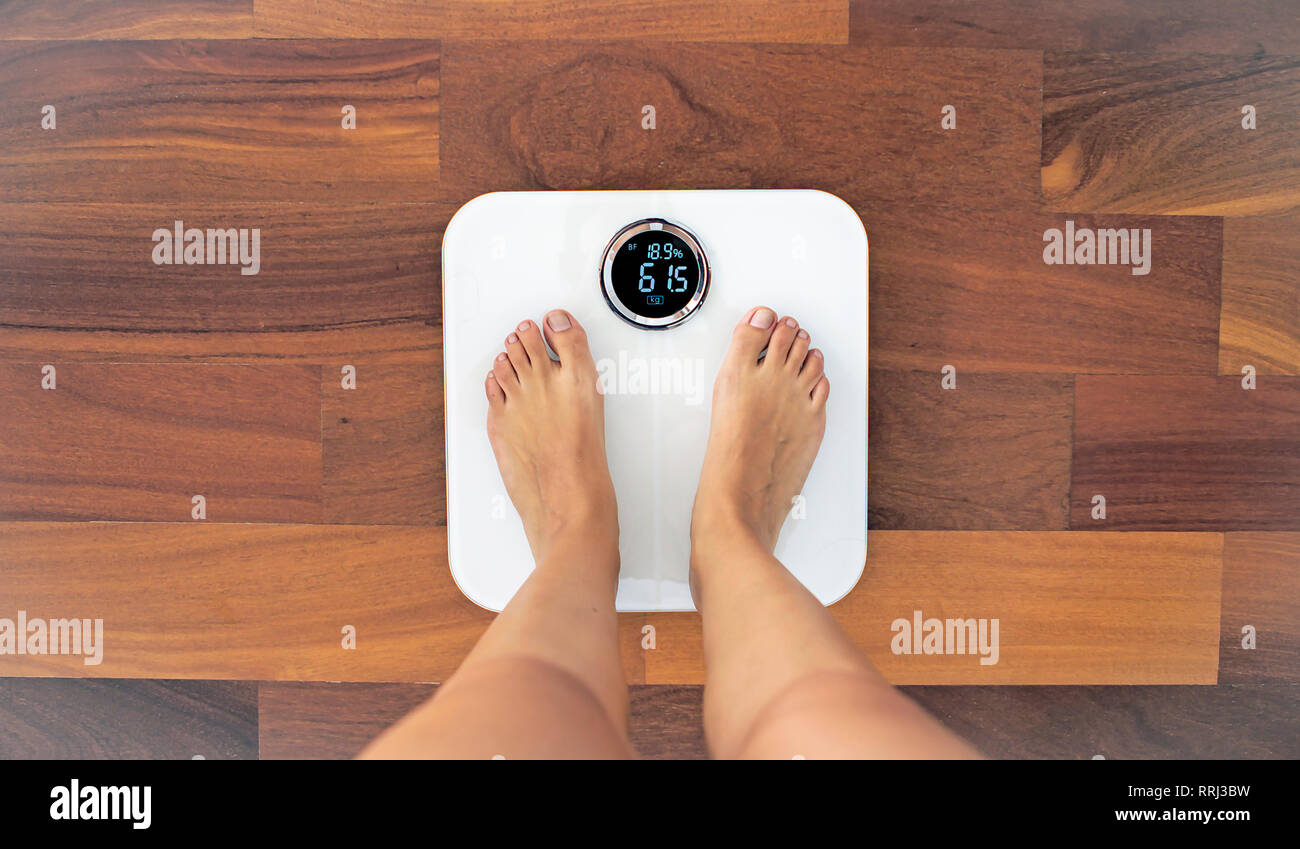 Woman bare feet standing on a digital scale with body fat analyzer that ...
