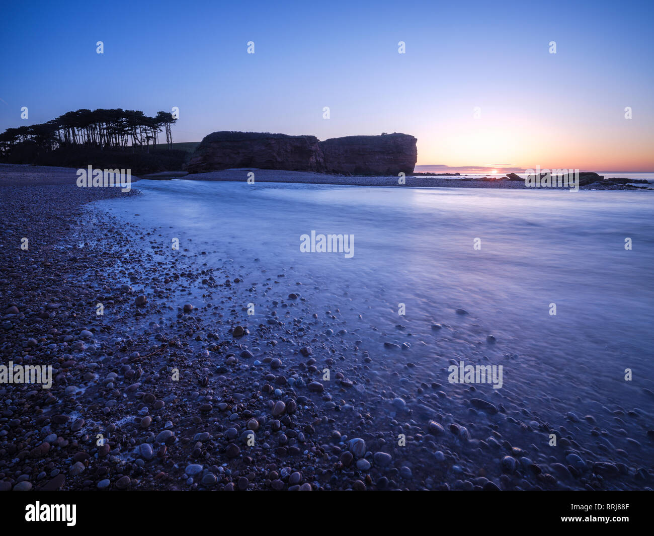 Sunrise behind the silhouetted cliff of Otter Head, where the River ...