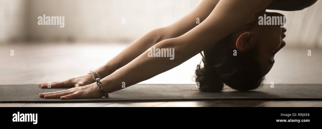 Horizontal photo sportive woman practice yoga doing downward facing dog ...