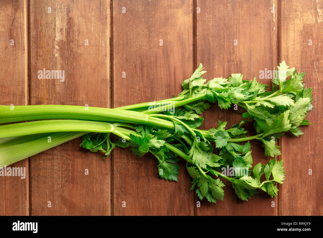 An overhead photo of fresh organic celery stalks with leaves on a dark ...